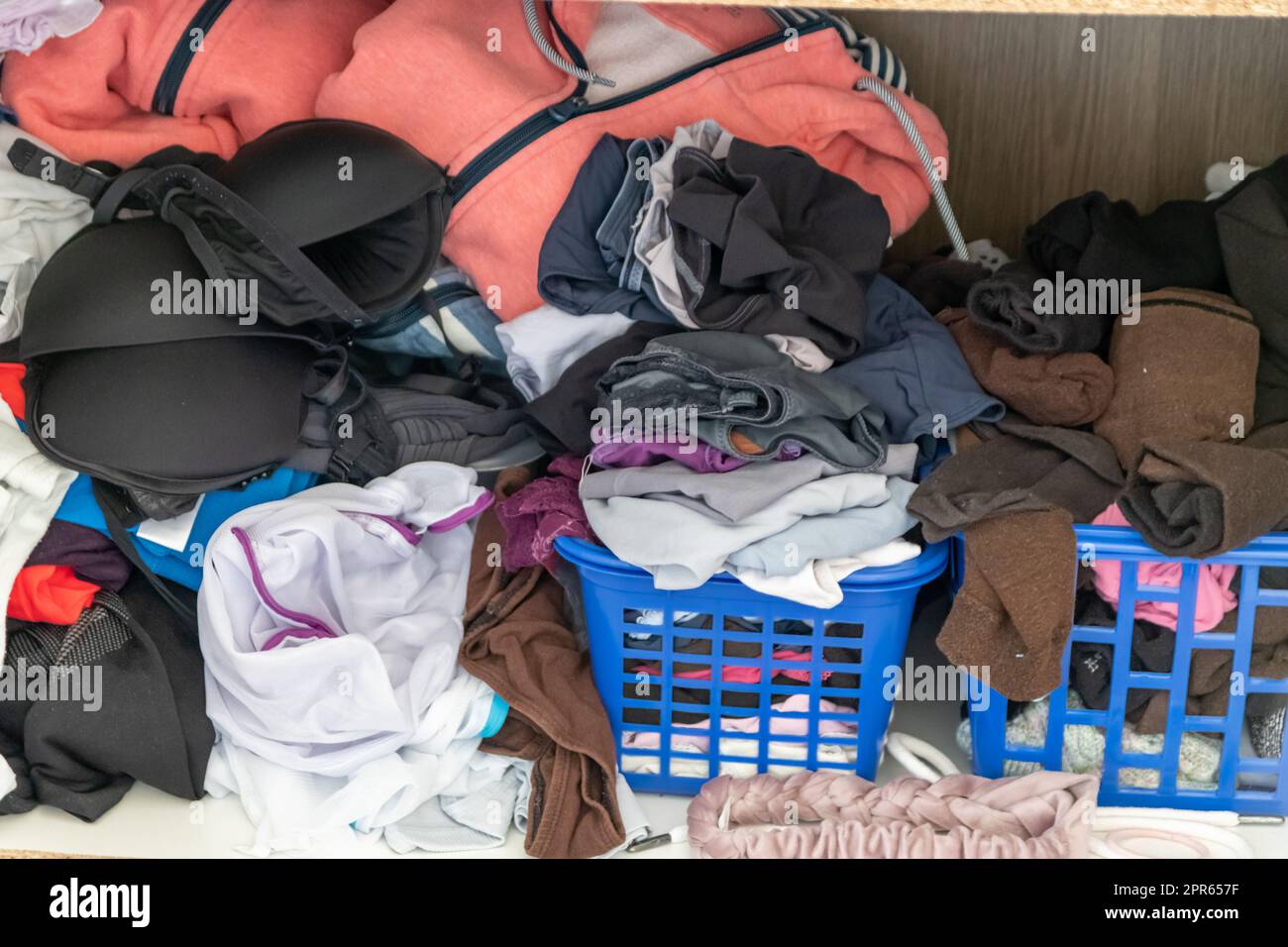 Chaotic wardrobe and sloppy closet shows many outfits of a woman with ...