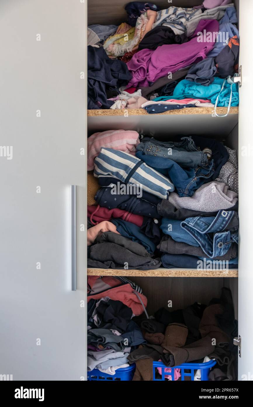 Chaotic wardrobe and sloppy closet shows many outfits of a woman with ...