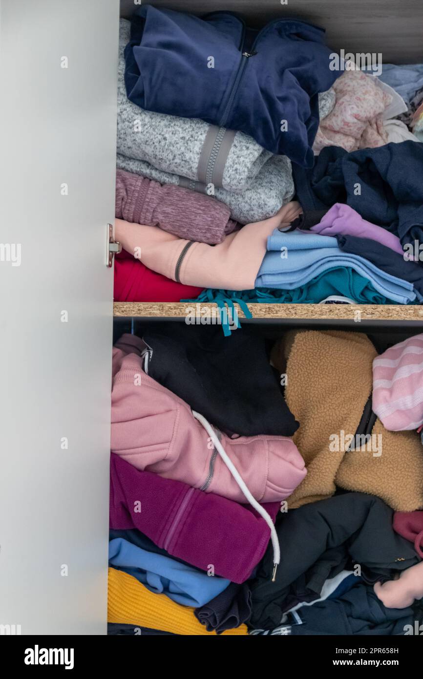 Chaotic wardrobe and sloppy closet shows many outfits of a woman with ...