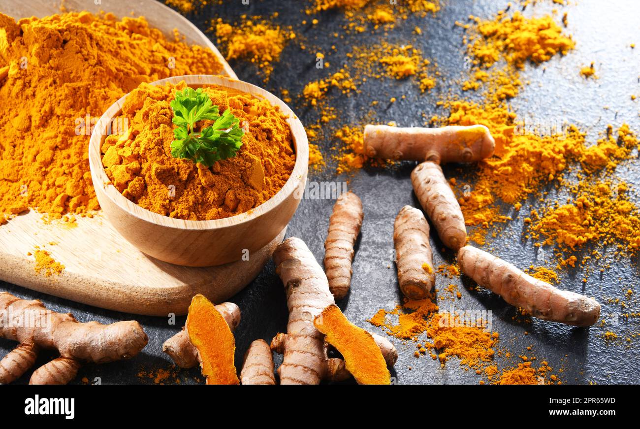 Composition with a bowl of ground turmeric and its fresh rhizome Stock ...