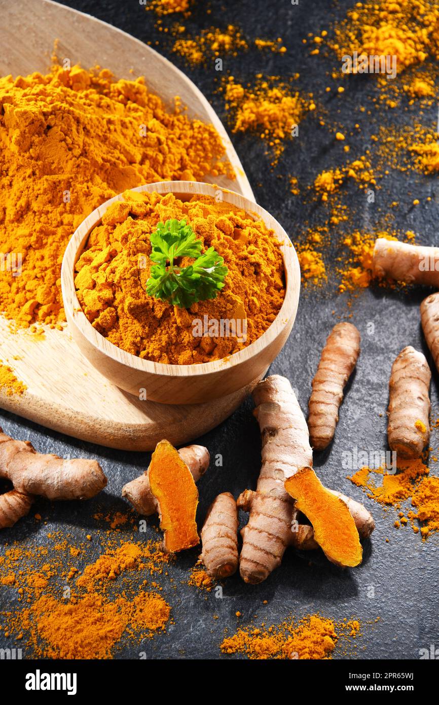 Composition with a bowl of ground turmeric and its fresh rhizome Stock ...