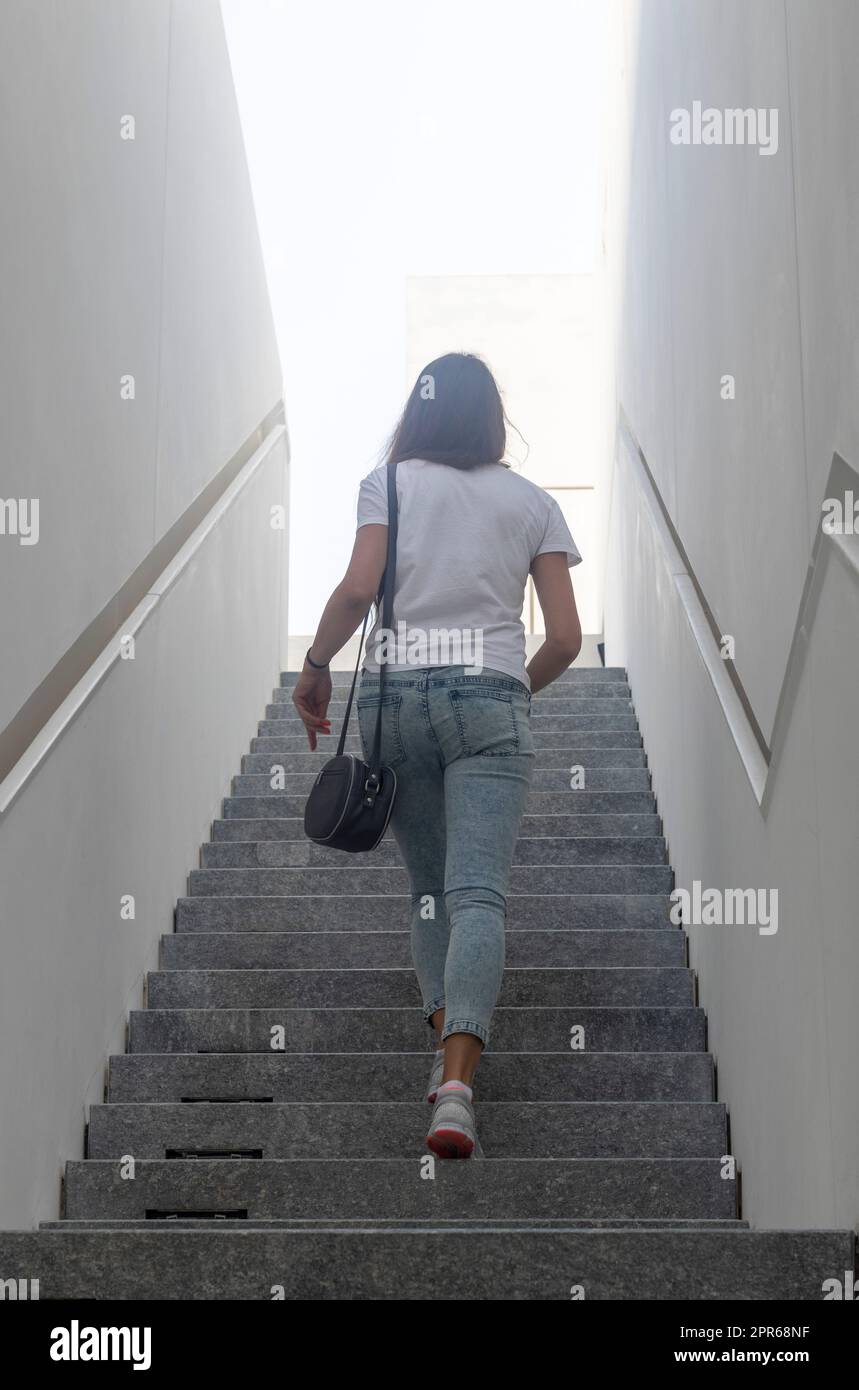 Shot of the young woman climbing up the stairs Stock Photo - Alamy
