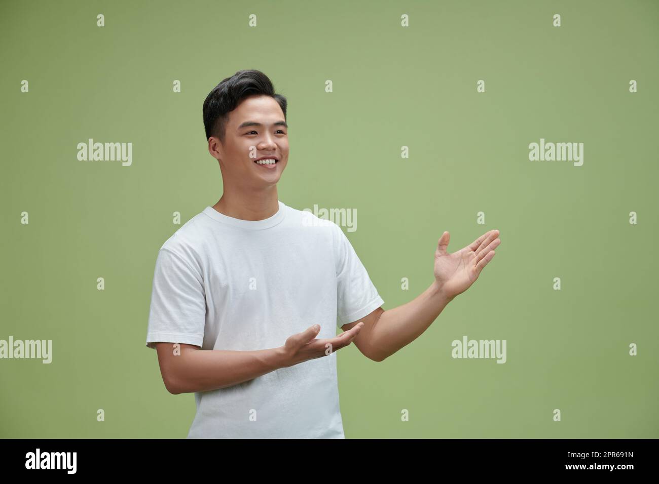 asian man pointing to the empty left side isolated green background ...