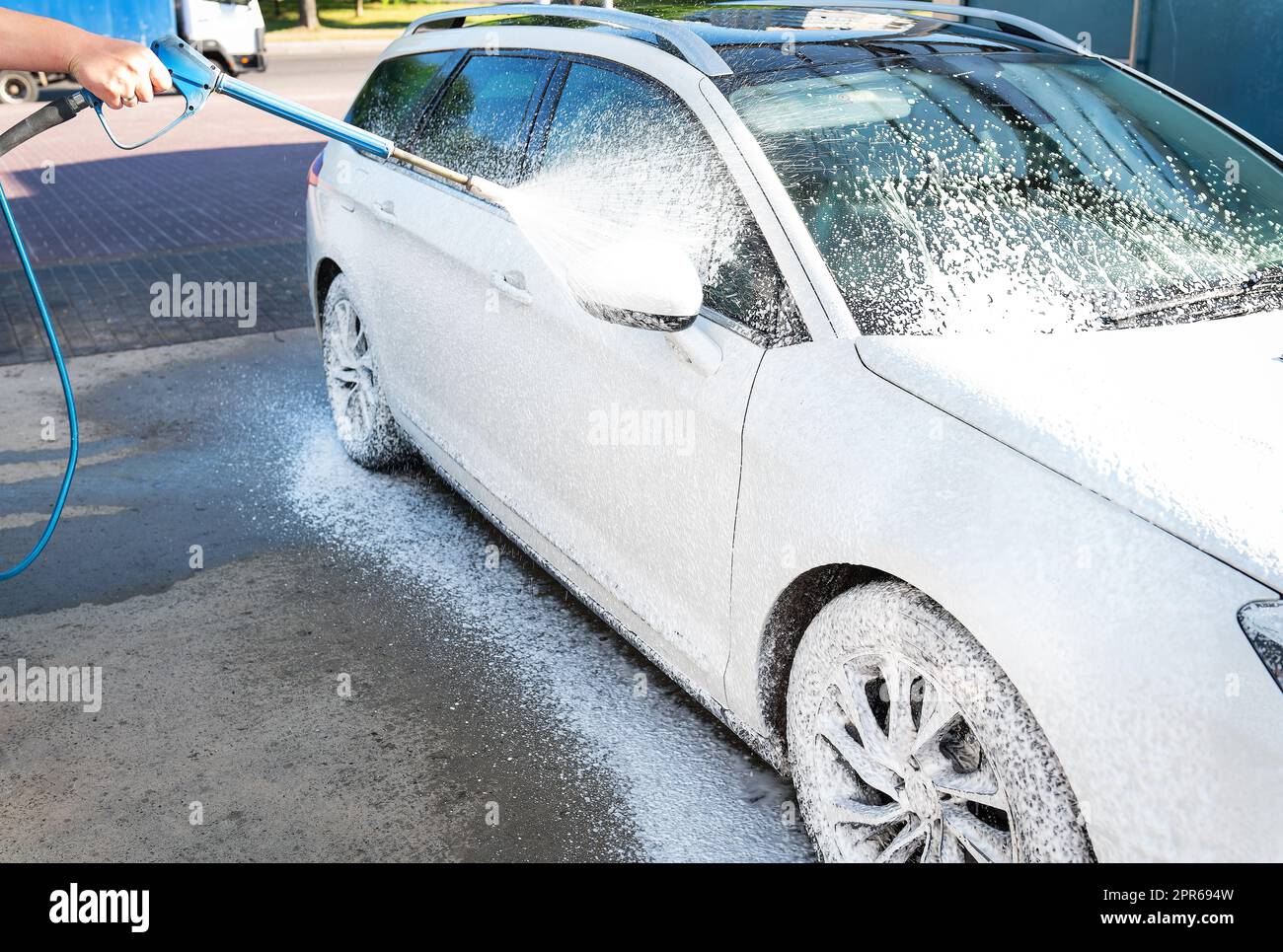Hand washing with high pressure water in a car wash outside. A jet of ...