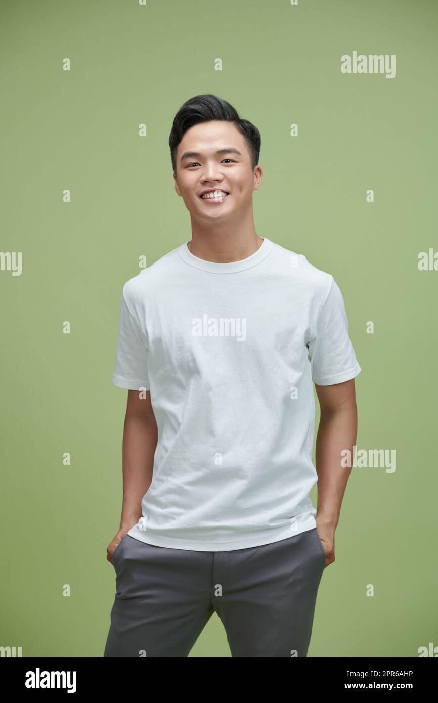 portrait of smiling young Asian man in plain casual clothes on light ...