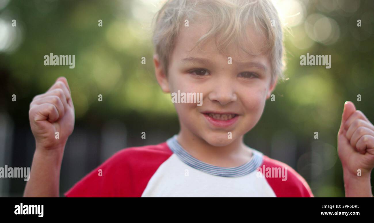 Happy child boy celebrating raising arms. Portrait of blond toddler infant boy feeling joy ...