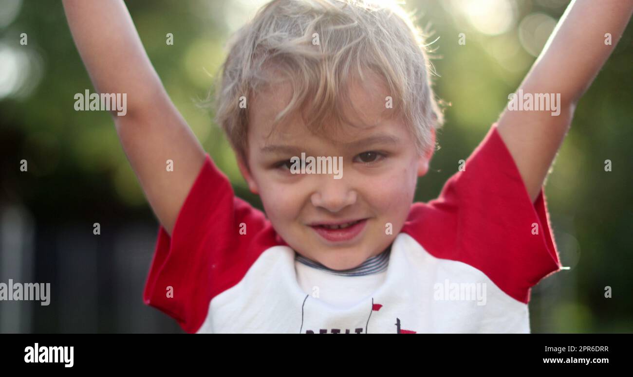 Happy child boy celebrating raising arms. Portrait of blond toddler infant boy feeling joy ...