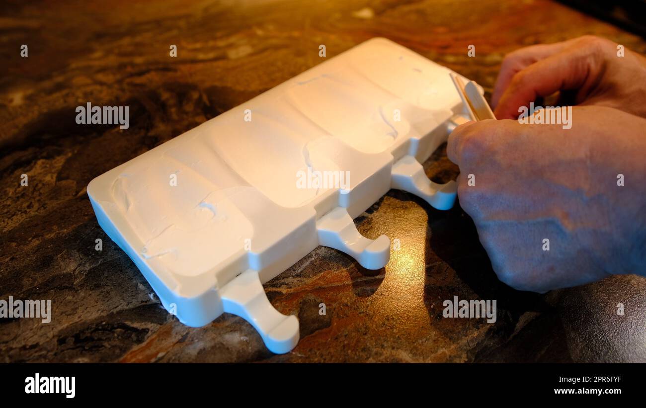 Making homemade popsicles. man pouring ice cream in freezer molds and ...