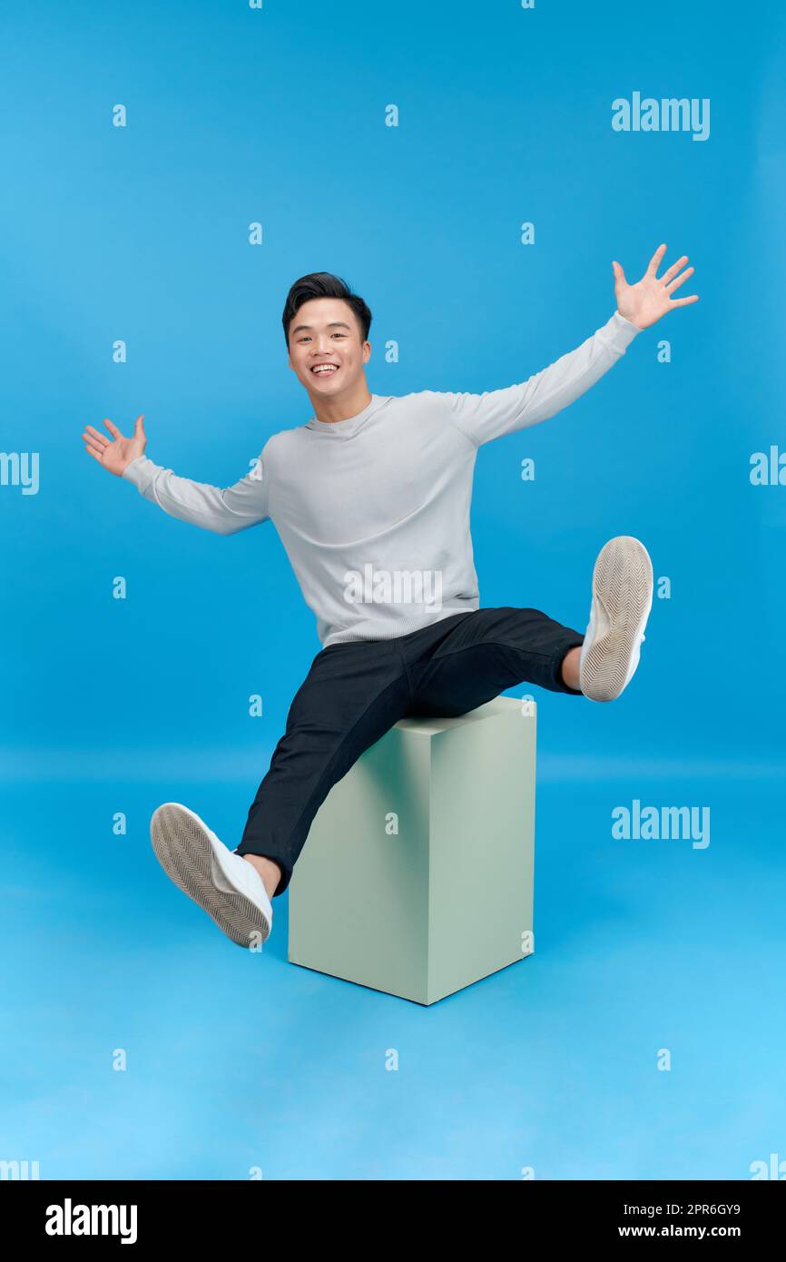 Full length photo of nice young guy sit white cube copyspace falling ...