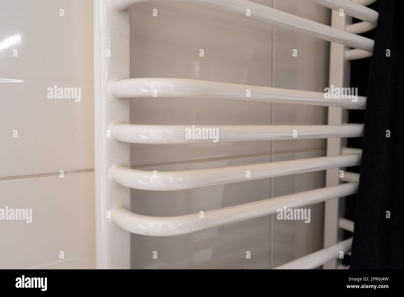 White ladder bathroom radiator and dark towel Stock Photo - Alamy
