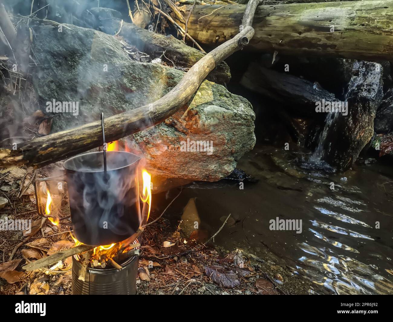 cooking water with open fire near a little brook Stock Photo - Alamy