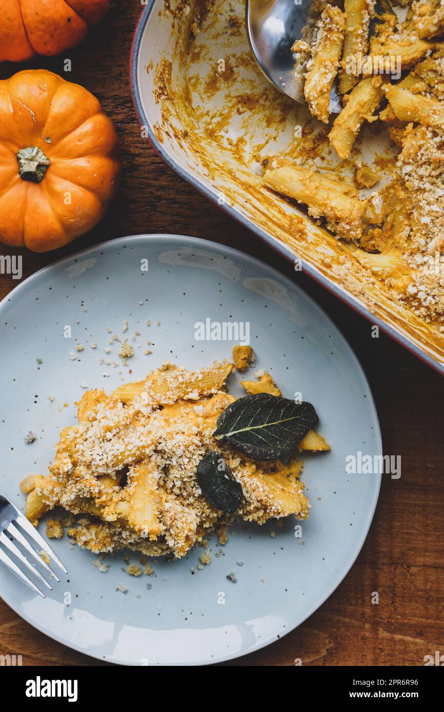 Vegan plant-based cheesy pumpkin pasta bake casserole served onto ...