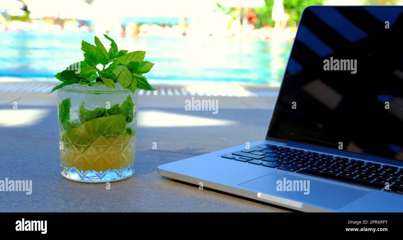 A photo of a laptop and a cocktail on the poolside Stock Photo - Alamy
