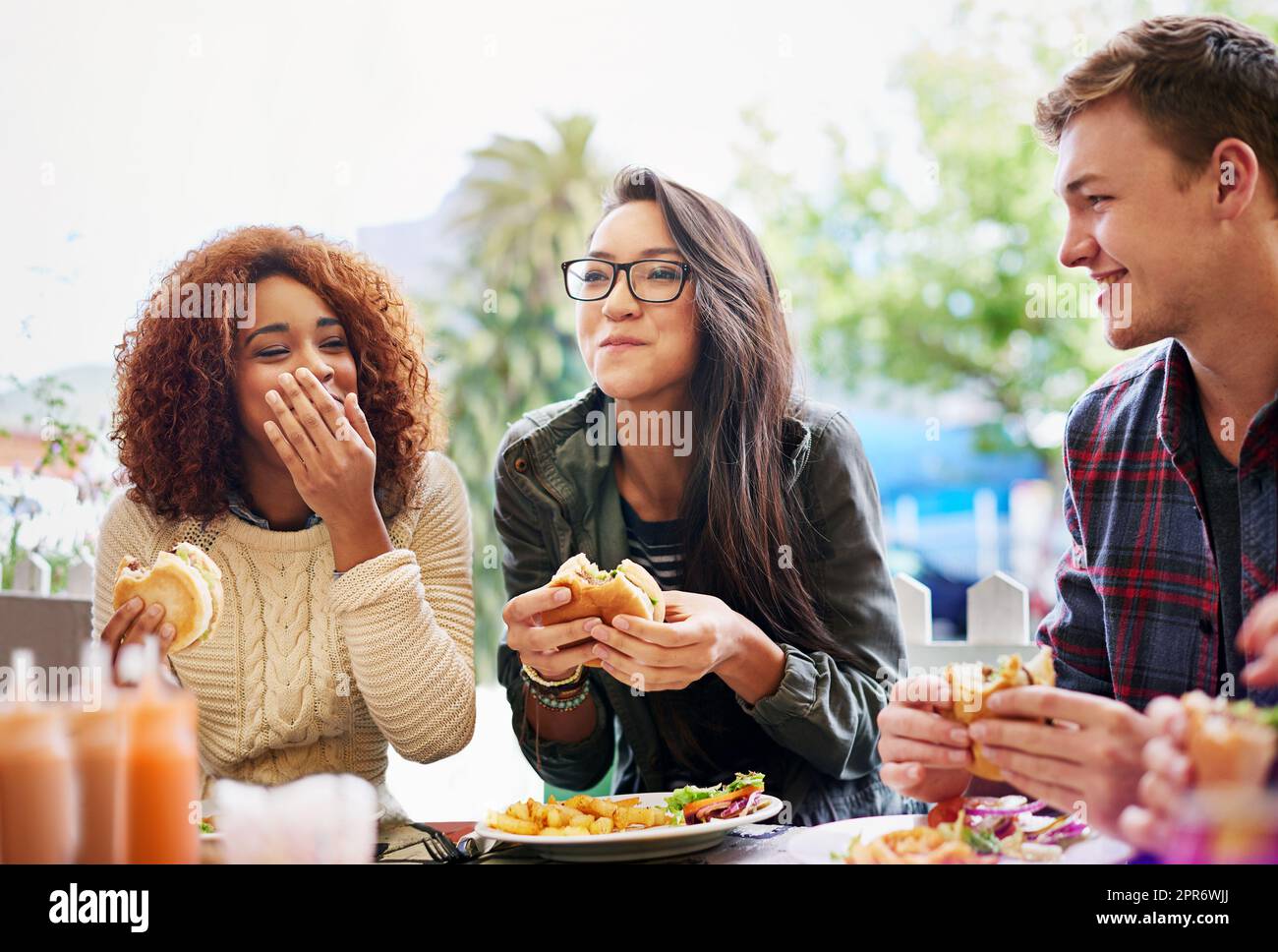 Three friends eating burgers outdoors hi-res stock photography and ...