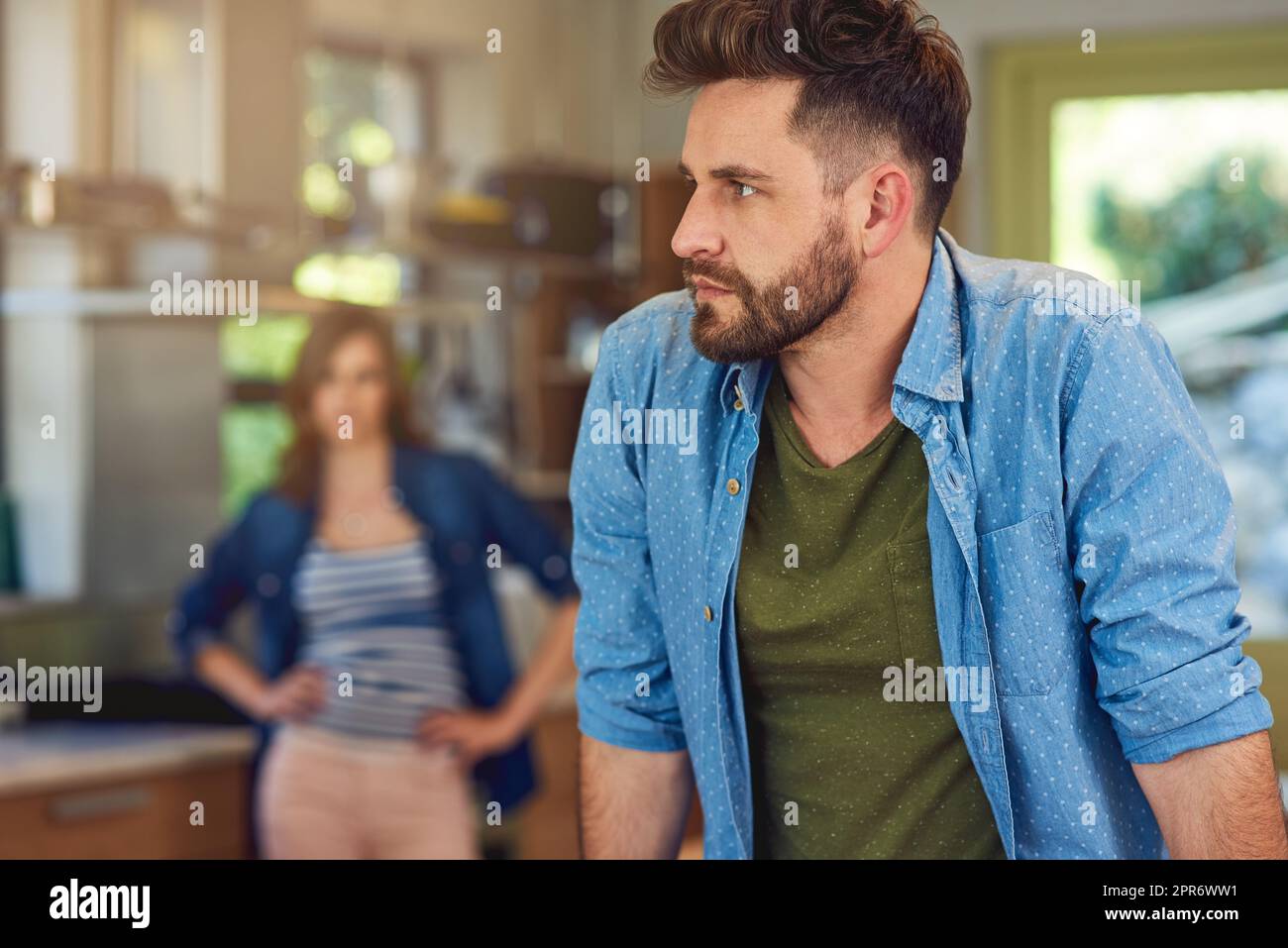 Should I stay or walk away. Shot of a young man looking upset after a fight with his wife who is ...