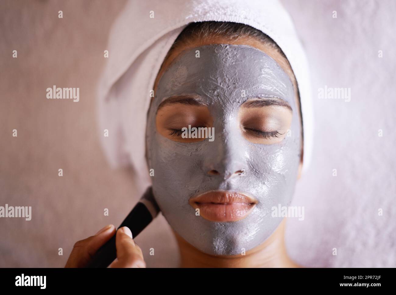 Pampering her skin with a facial treatment. Shot of a young woman enjoying a facial treatment at ...