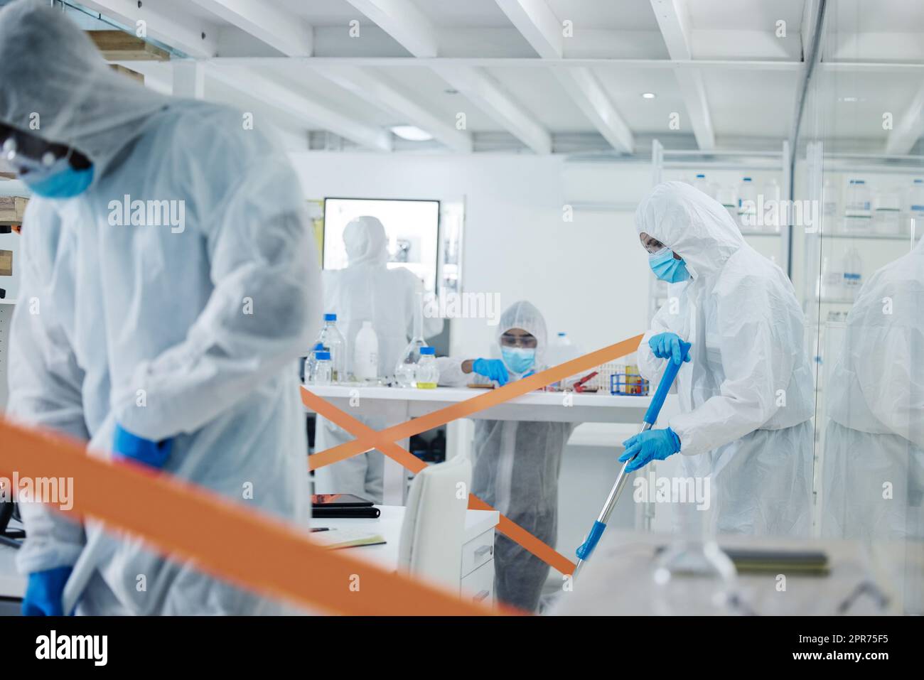 Cleaning up is a team effort. Shot of a group of scientists cleaning up a mess at a lab Stock ...