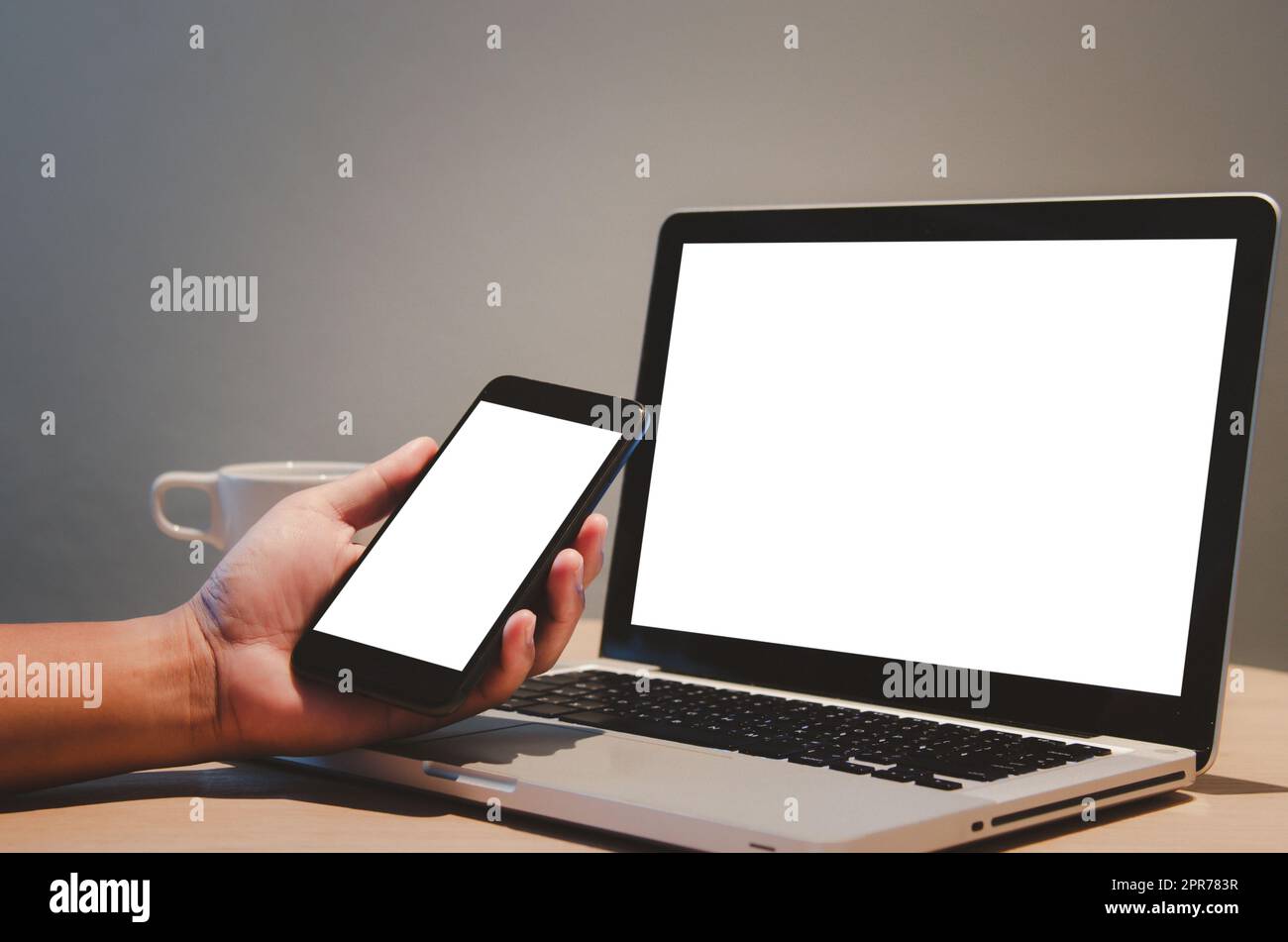 man hand holding mobile smartphone and computer laptop mock up blank ...