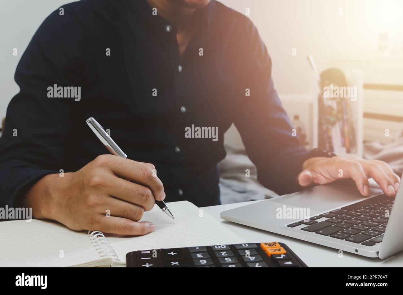Businessman hand holding pen writing notebook and using keyboard ...