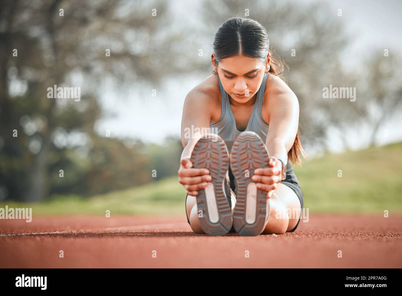 Preparing her body for a challenge. a young athlete stretching her legs ...