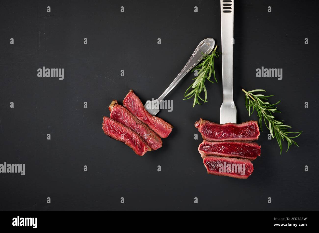 Fried pieces of beef strung on an iron large fork, black background ...