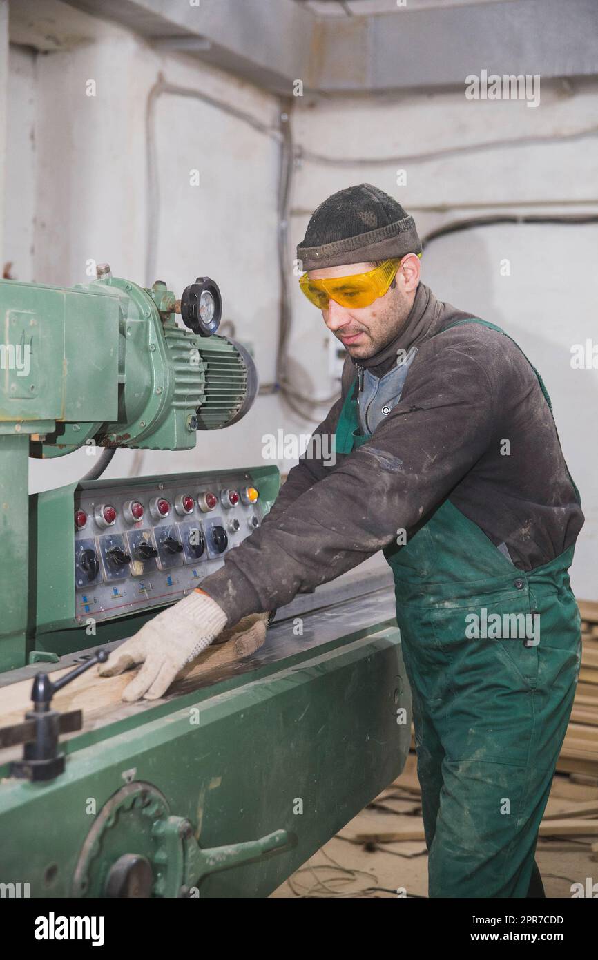 worker in a factory passes boards through a jointer Stock Photo - Alamy