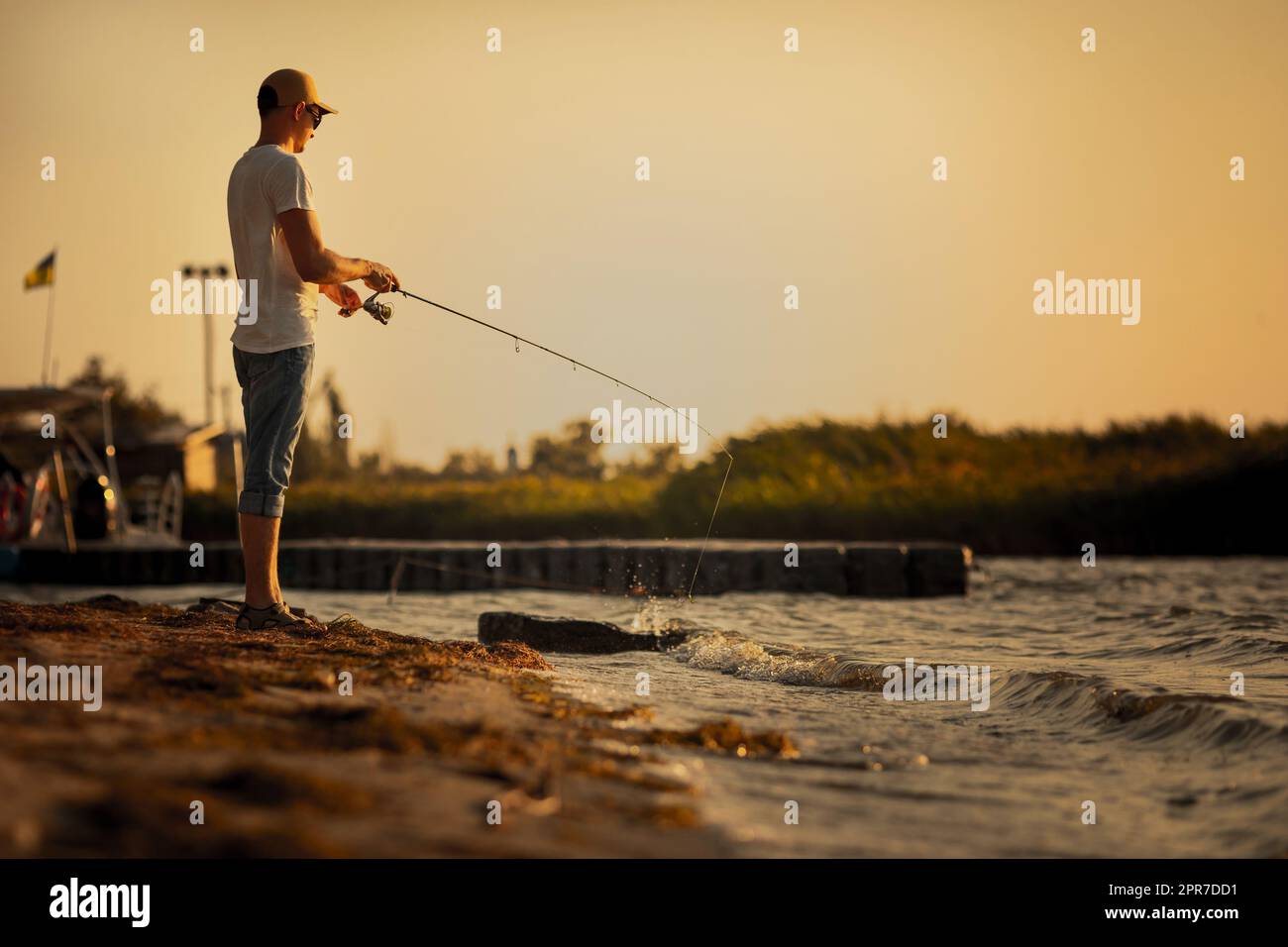 Young man fishing at sea Stock Photo - Alamy