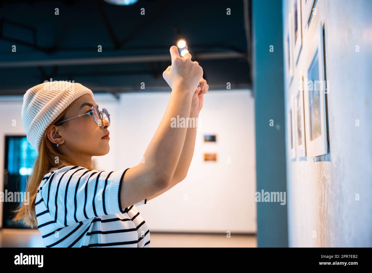 Visitor woman standing takes picture art gallery collection in front ...