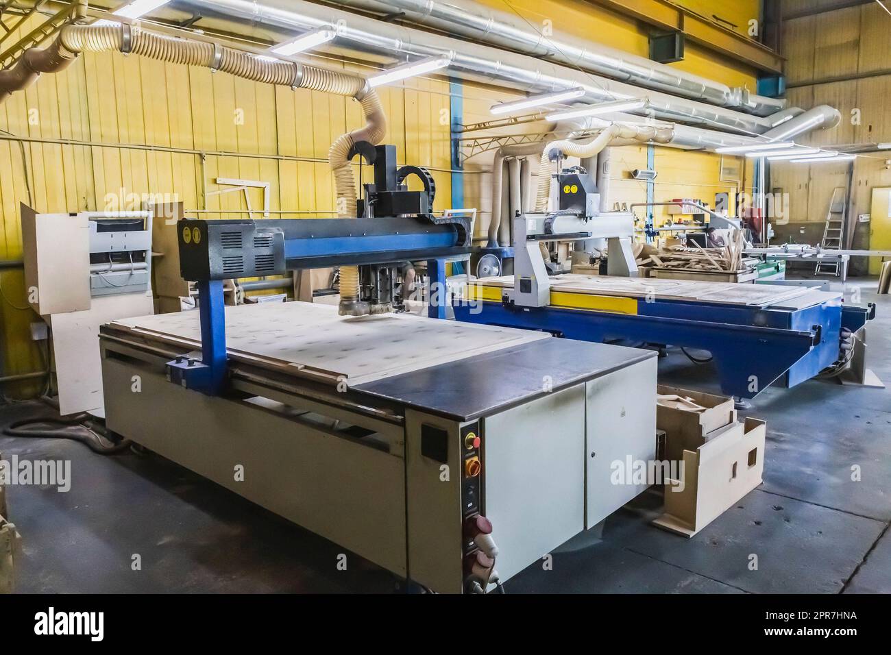 two large cnc machine cuts blanks of various shapes on a plywood sheet ...