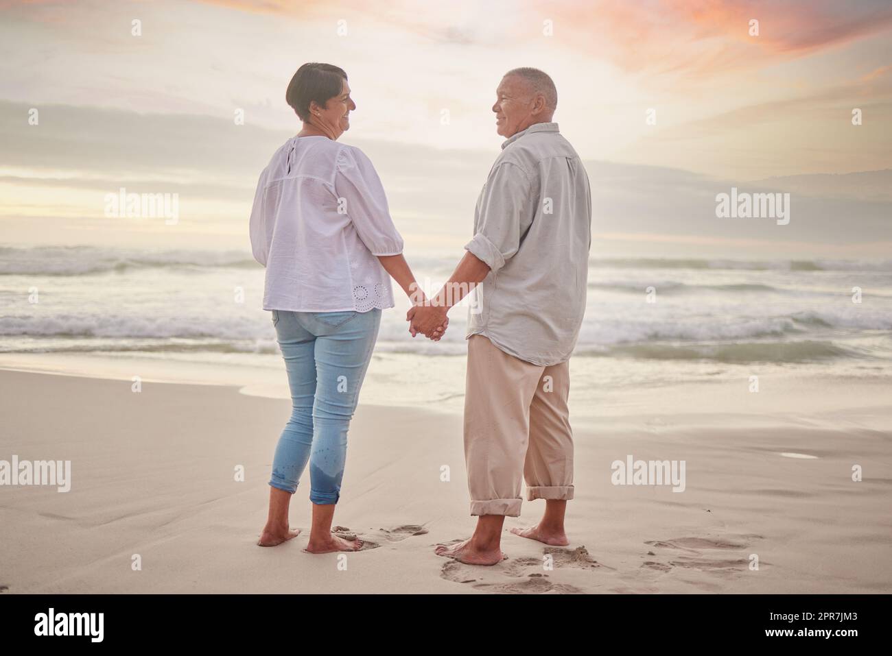 Rearview Affectionate Mature Mixed Race Couple Standing Hand In Hand On