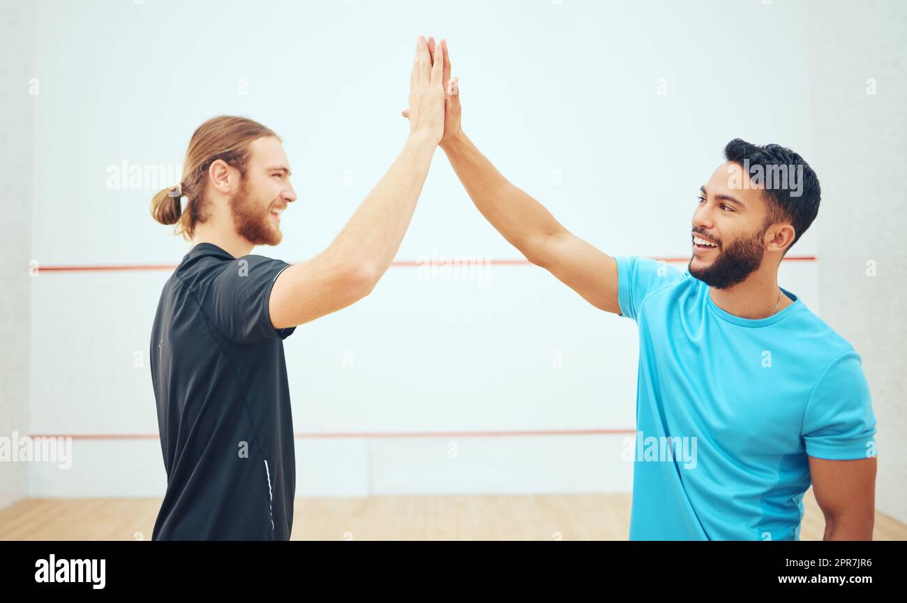Two athletic squash players giving high five before game on court. Team ...