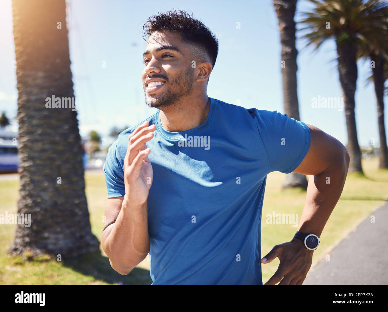 Happy smiling young mixed race fit man enjoying a run in a park during ...