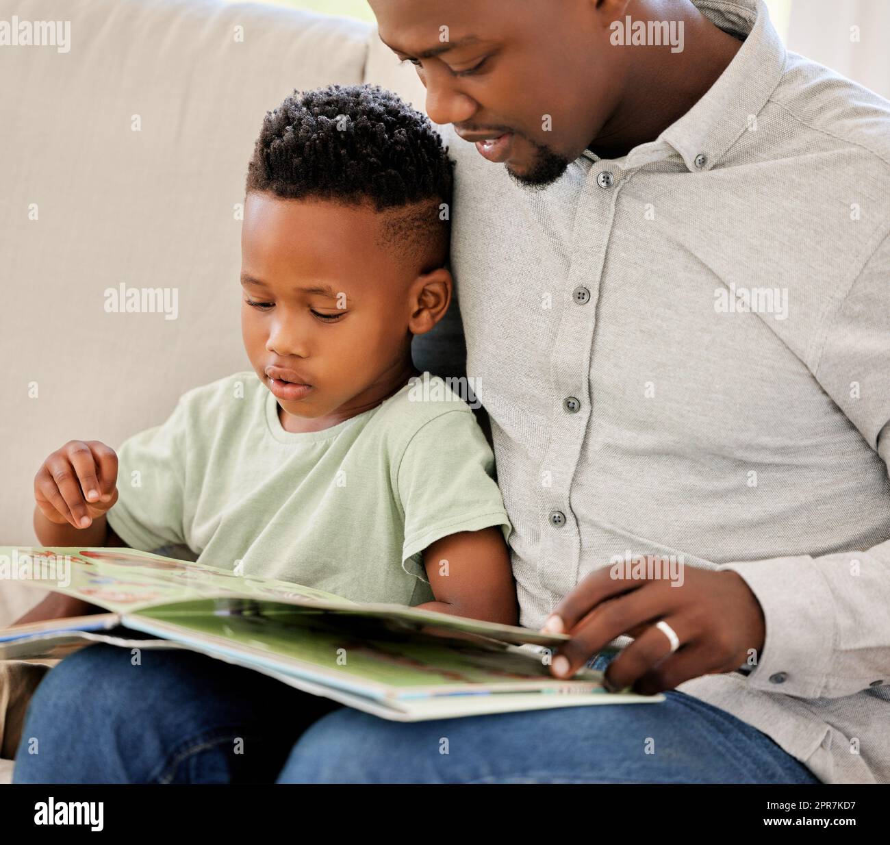 Young content African american father reading a book with his son ...