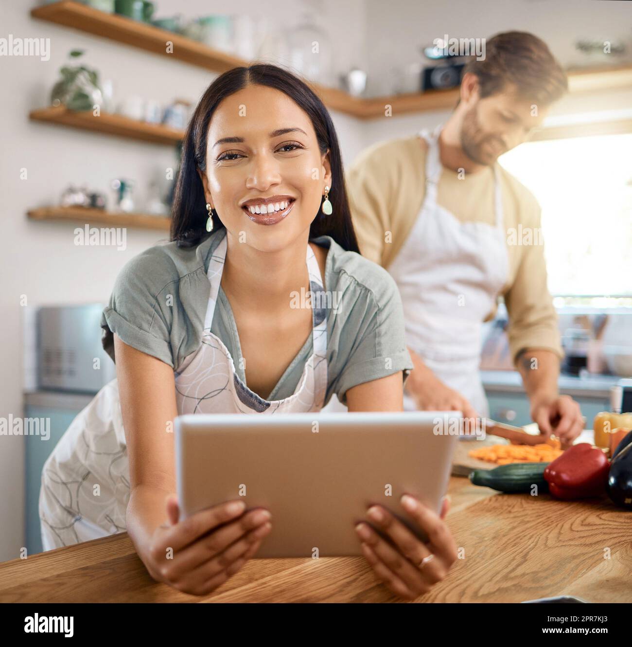 Portrait of beautiful young woman browsing on digital tablet while her ...