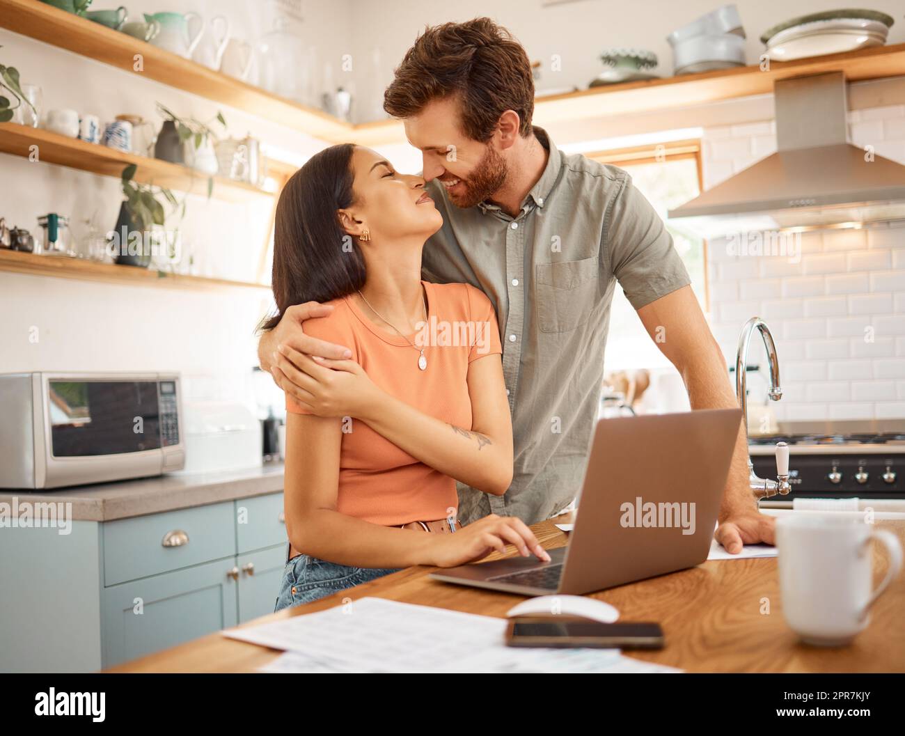 Young Happy Interracial Couple Bonding While Going Through Paper And Using A Laptop Together At