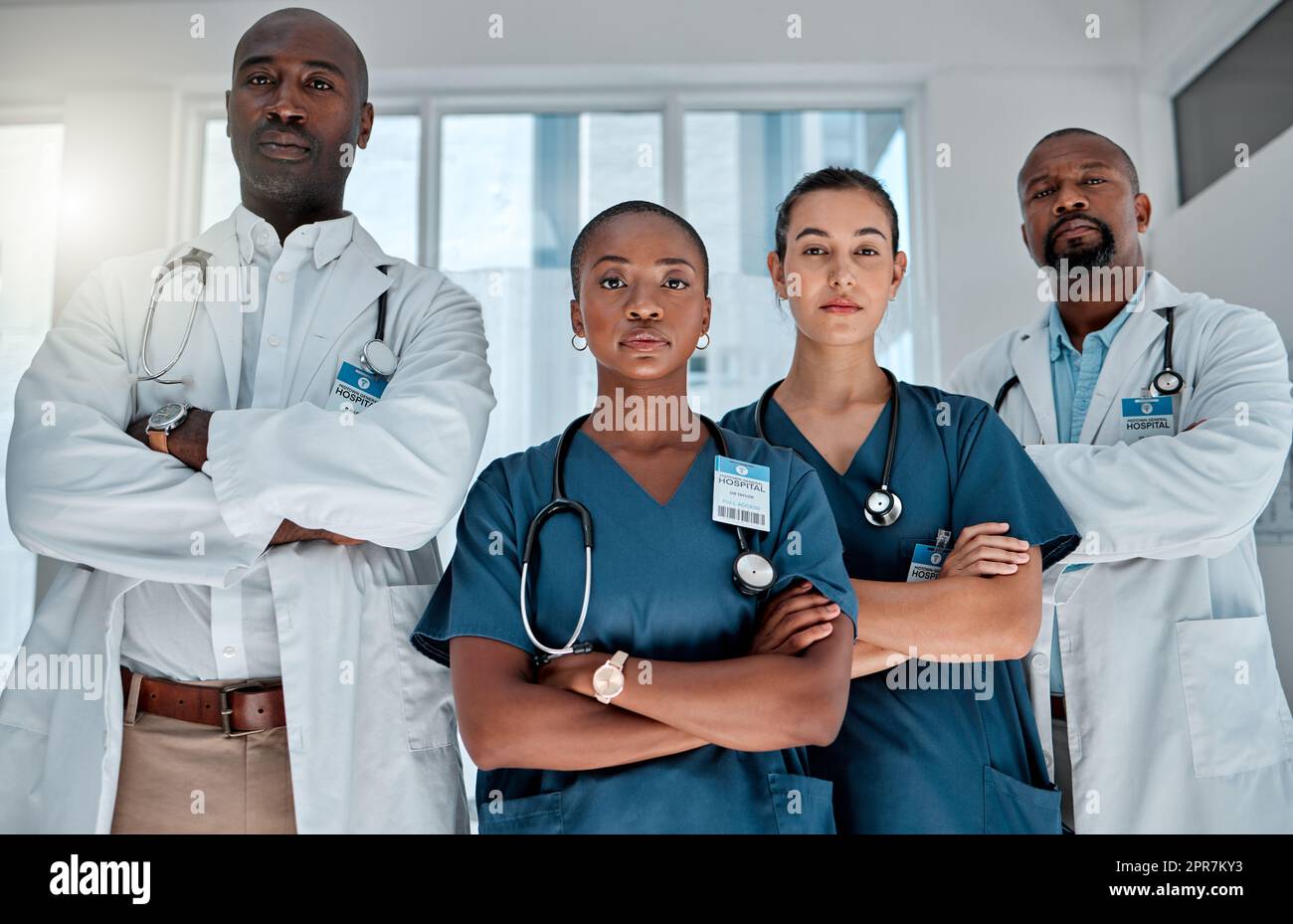 Group of serious doctors standing with their arms crossed while working ...