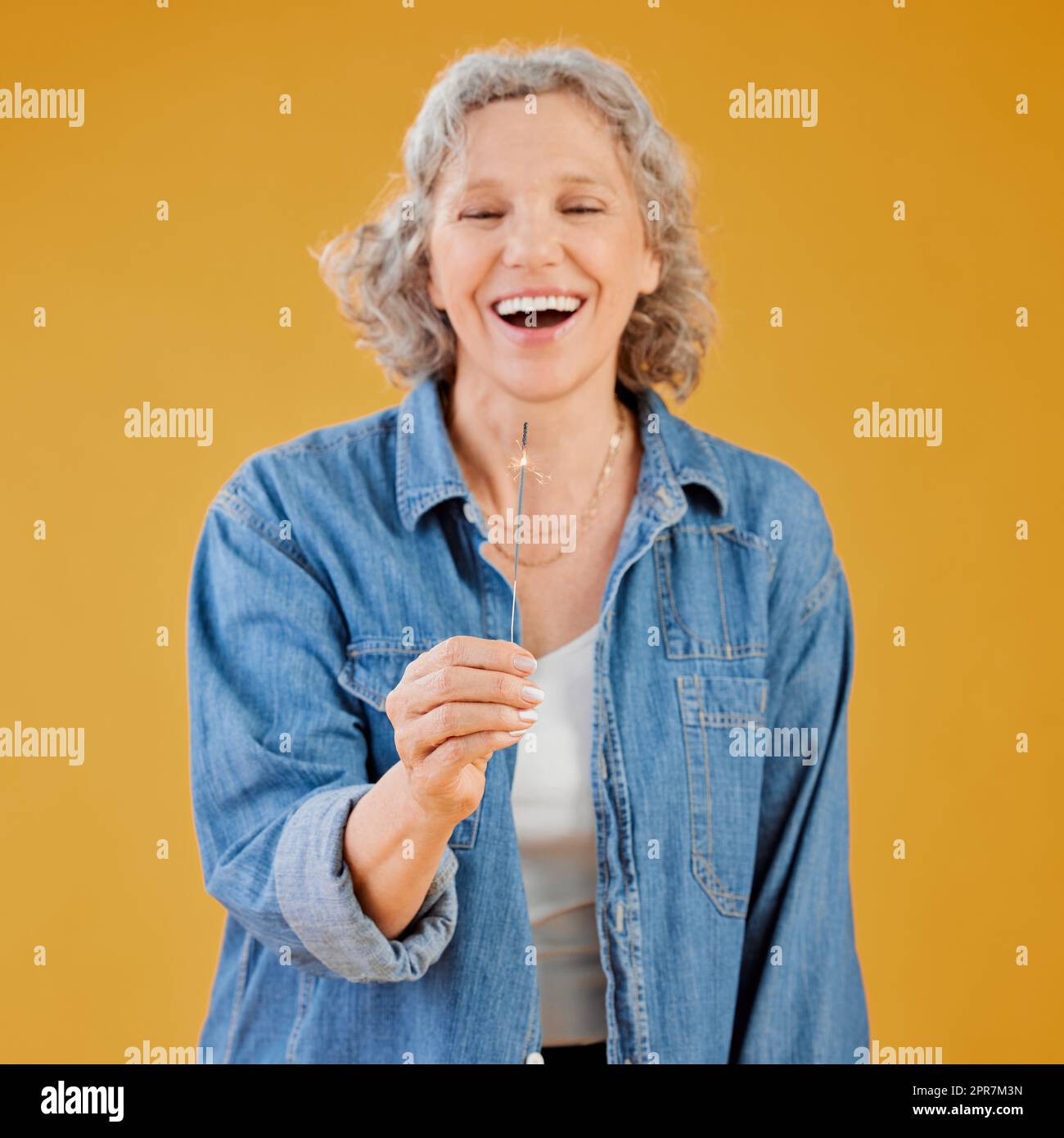 One Happy Mature Caucasian Woman Playing With A Sparkler On Her Birthday While Posing Against A