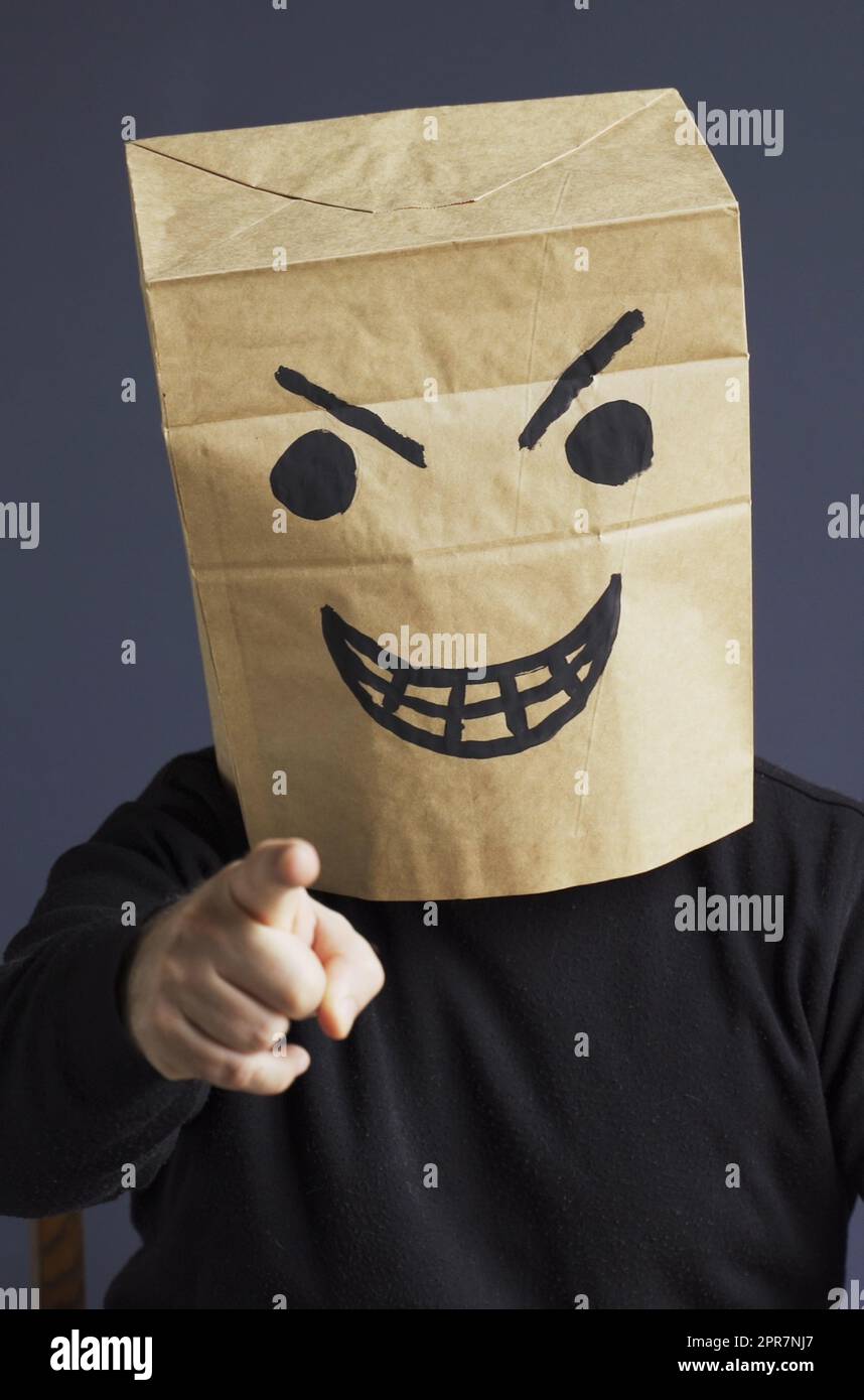 A man in a black turtleneck with a paper bag with an angry emoticon on ...