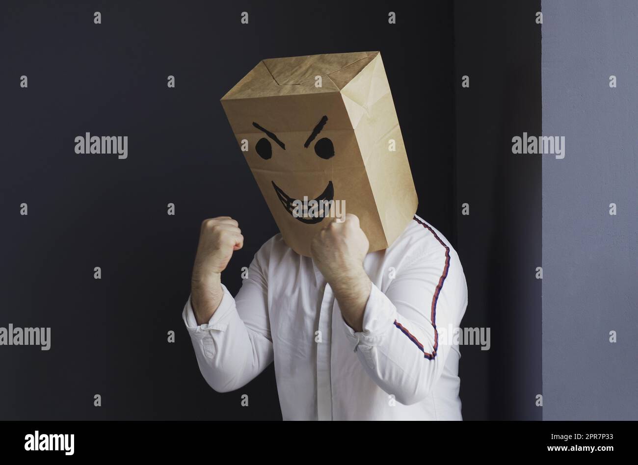 A man in a white shirt with a paper bag with an angry emoticon on his ...