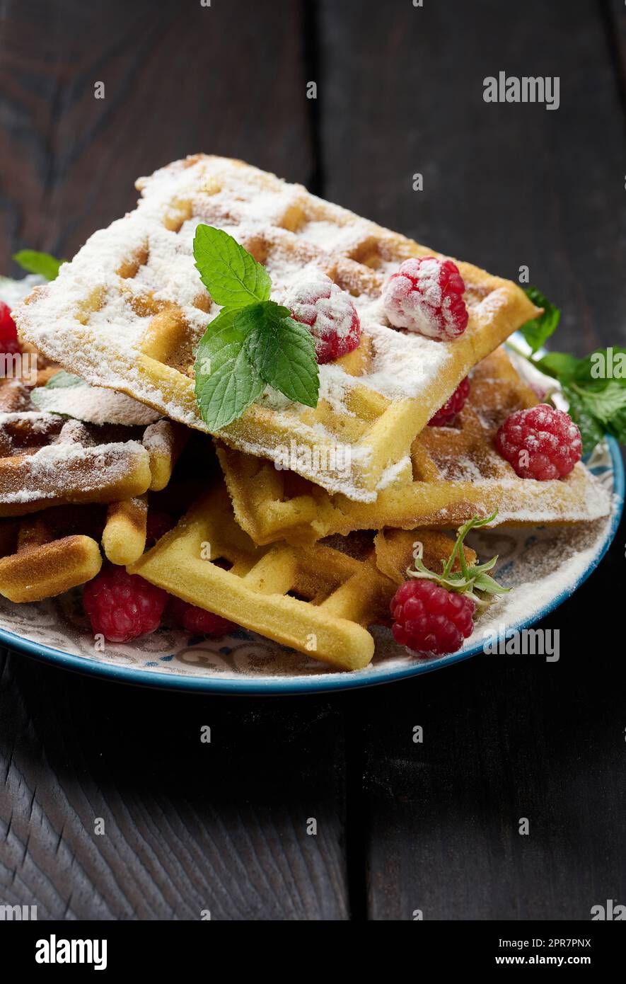 Stack of baked Belgian waffles with ripe red raspberry sprinkled with ...