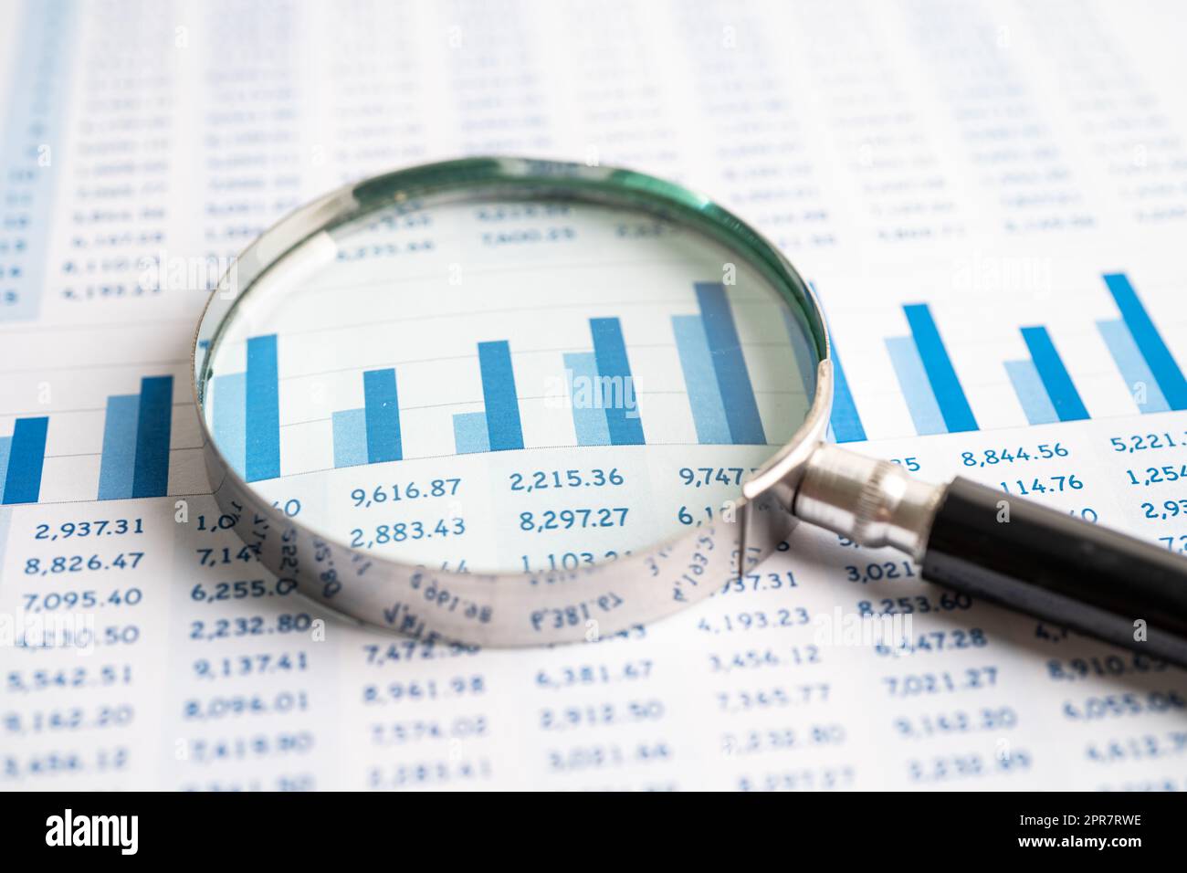 Magnifying glass on chart graph spreadsheet paper. Financial ...