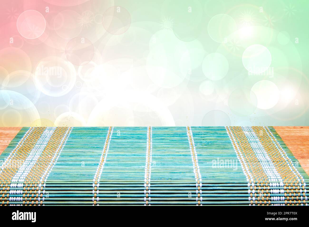 A green yellow bamboo mat on a rustic wooden table over bright blurred ...