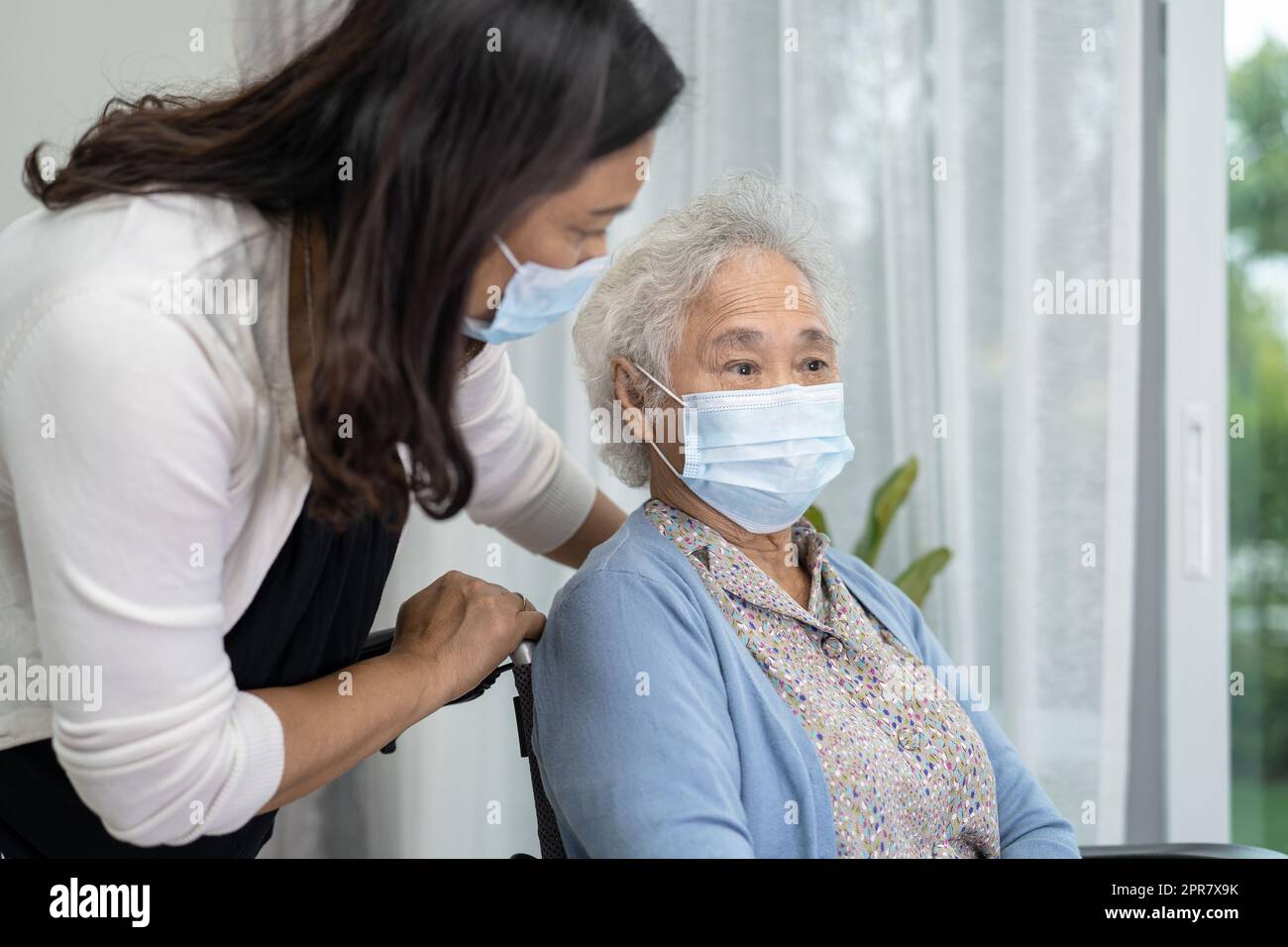 Help Asian senior or elderly old lady woman sitting on wheelchair and wearing a face mask for ...