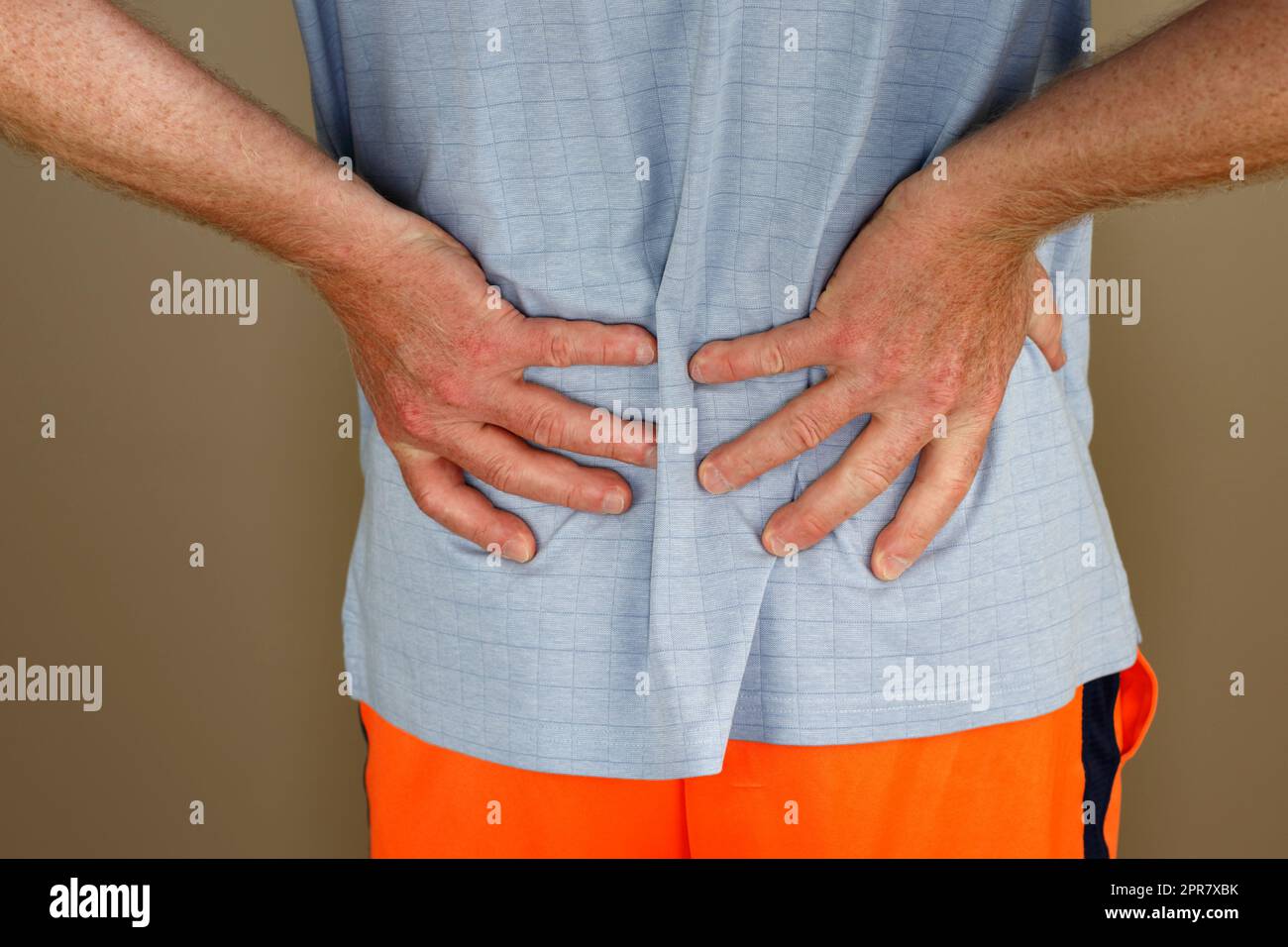 Adult Man Self Massaging His Low Back with Both Hands Through a Shirt ...