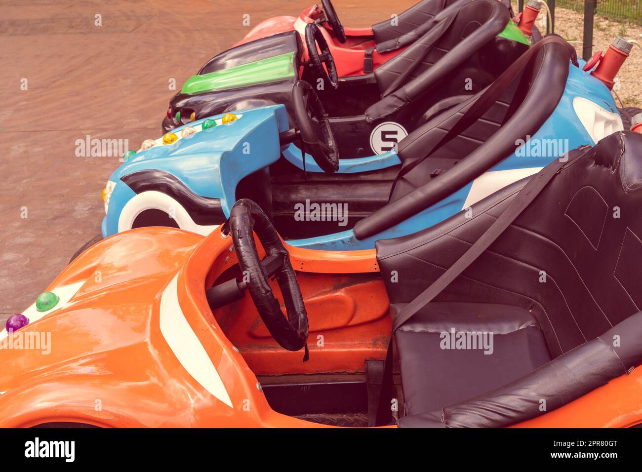 A row of dodgem cars are being charged at a power charging station ...