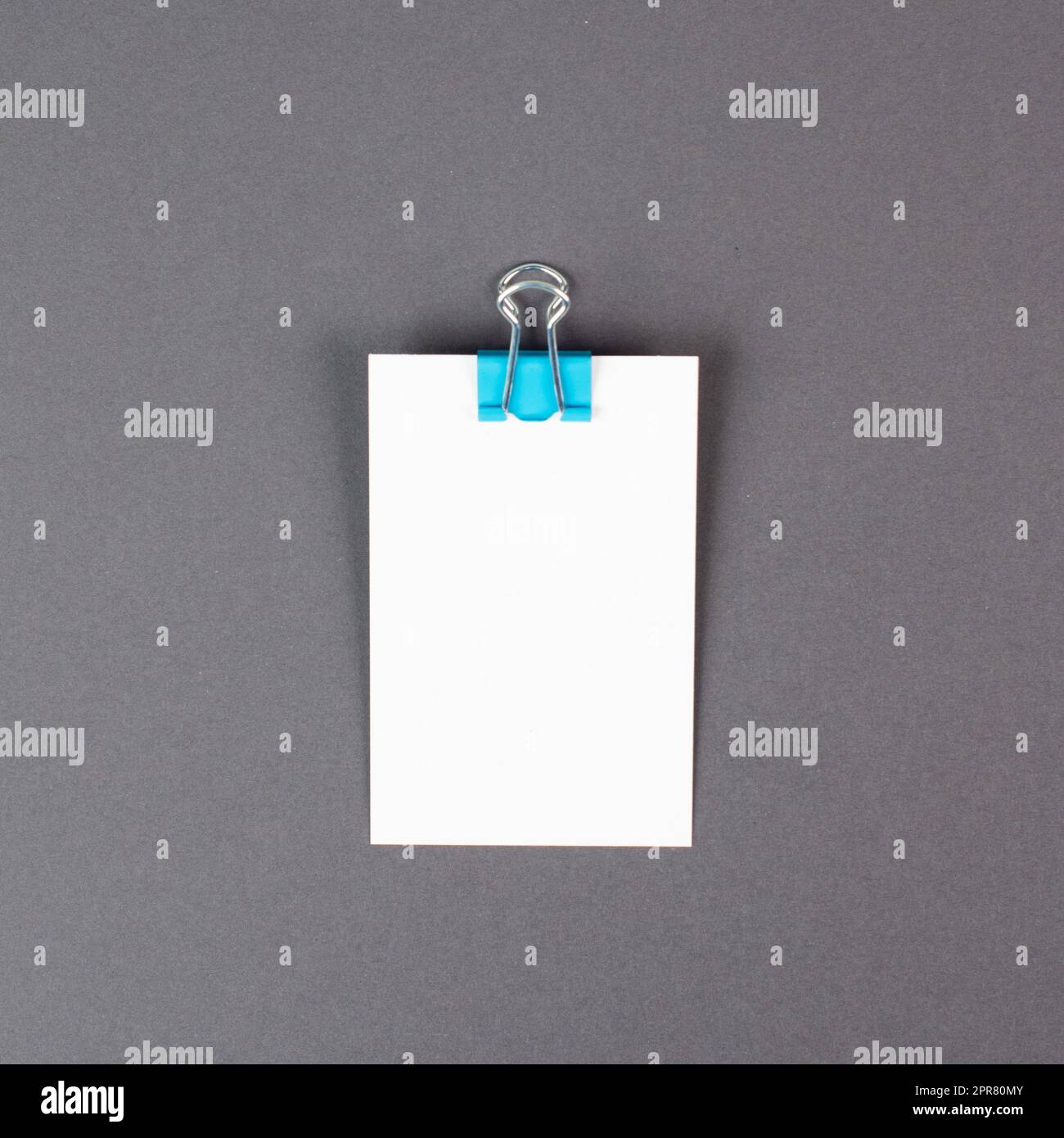 Blank white paper with a paperclip on a colored background, copy space ...