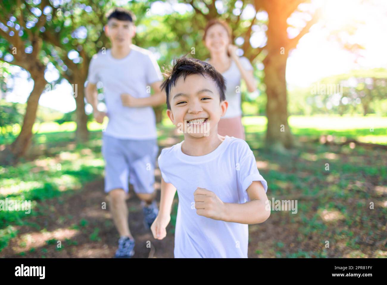 Happy boy Jogging with parents in the city park Stock Photo - Alamy