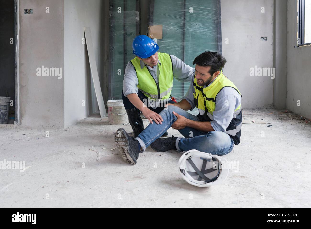 Young caucasian man in safety vest gripped his knee and screams in pain ...
