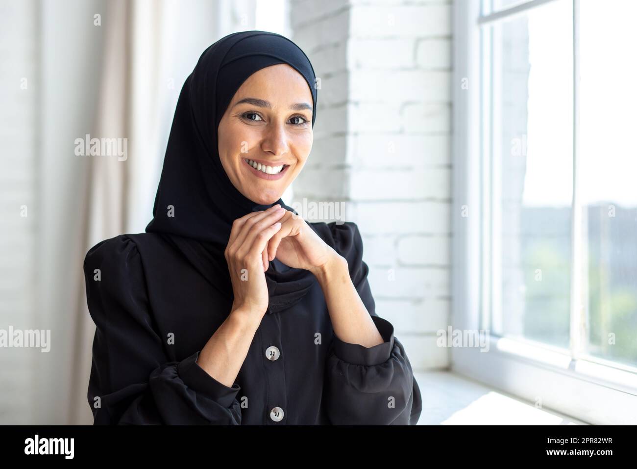 Portrait of a young beautiful woman in a black burqa, hijab standing by ...