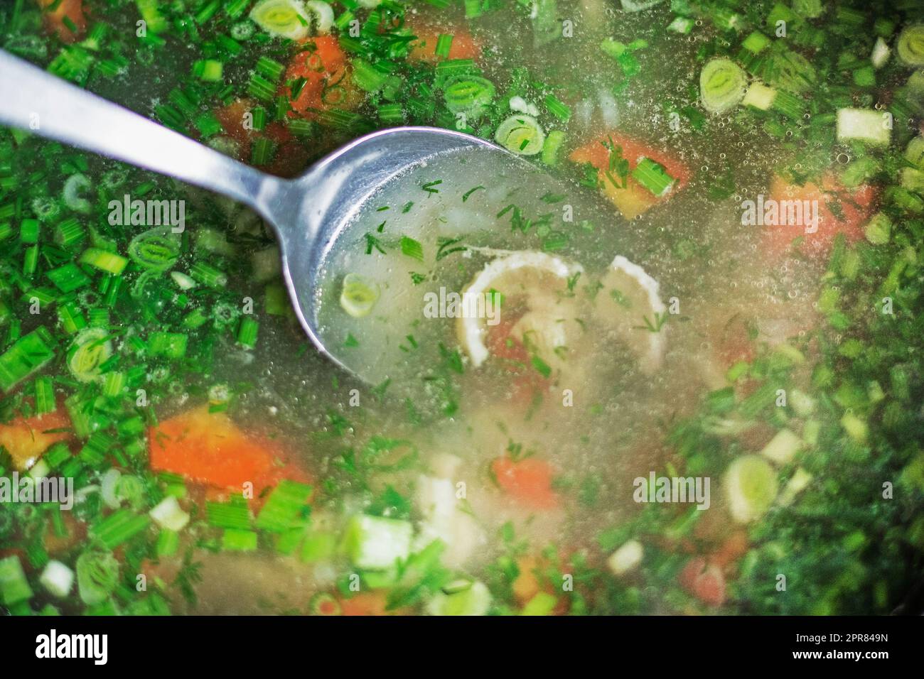 stir the boiling soup with herbs with a spoon. cook at home Stock Photo ...
